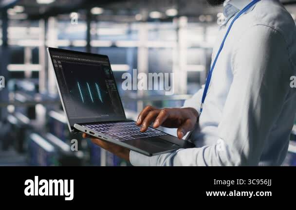 Engineer and colleague in data center reviewing large language model visualizations on laptop ...