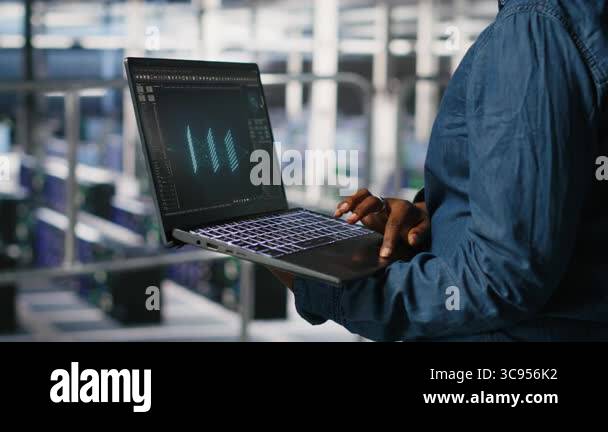 Close up of admin in data center using laptop to monitor neural network ...