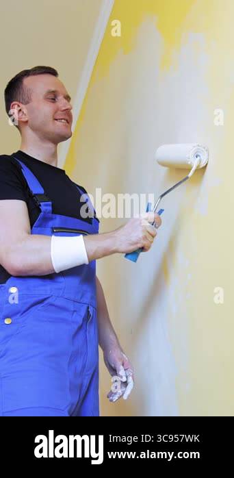 Man painting walls at home. Handsome man in work overalls paints the ...