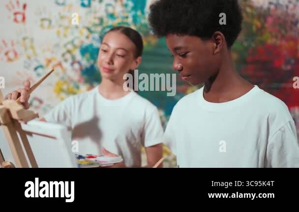 Diverse happy children paint canvas together with colorful stained wall ...