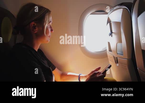 Passenger woman is flying in plane. Girl using phone sitting by ...
