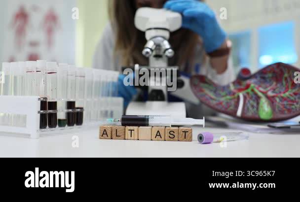 Scientist uses microscope to analyze blood samples and to study ALT AST ...