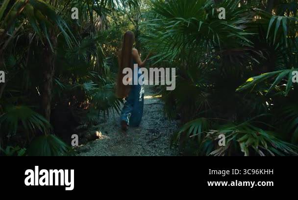 Woman walking barefoot along tropical forest path with long hair ...