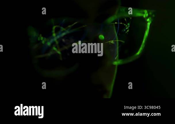 Close up of eyeglasses reflecting bright green digital patterns ...