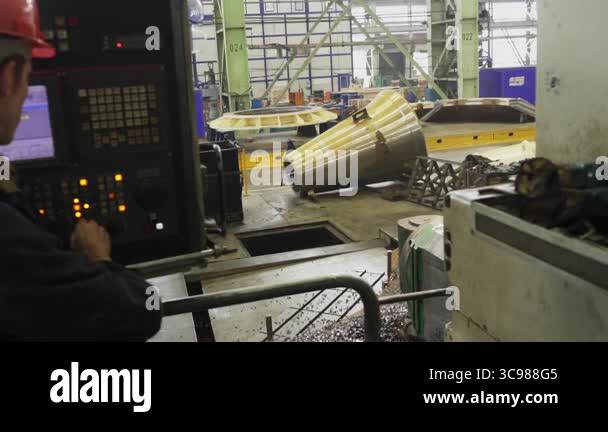Skilled factory worker operating a cnc machine, producing metal parts ...