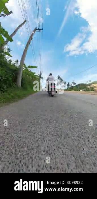 Vertical video. Man on Scooter Driving into Curve on Mixed Surface Road ...