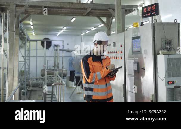 Factory engineer inspecting industrial equipment inside manufacturing ...