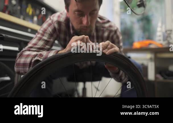 Male bicycle mechanic carefully replacing a road bike tire on a high ...