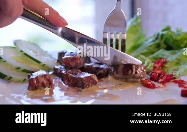 A person is eating a meal with a knife and fork. The plate has a ...