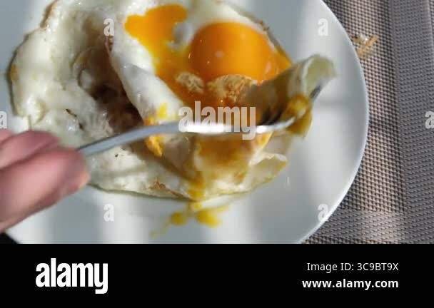 eating fried eggs with a bread on a green plate. close-up. angle view ...
