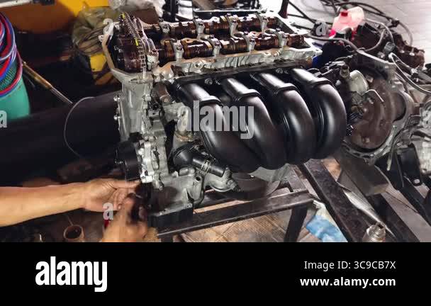 Service man are diligently working on a car engine inside a garage ...