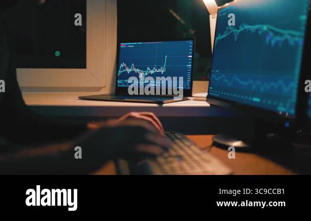 Late at night, a trader focuses on charts and data displayed on ...