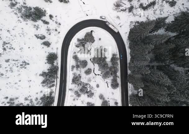 An aerial view showcasing a beautifully winding road snaking through a tranquil snowy forest ...