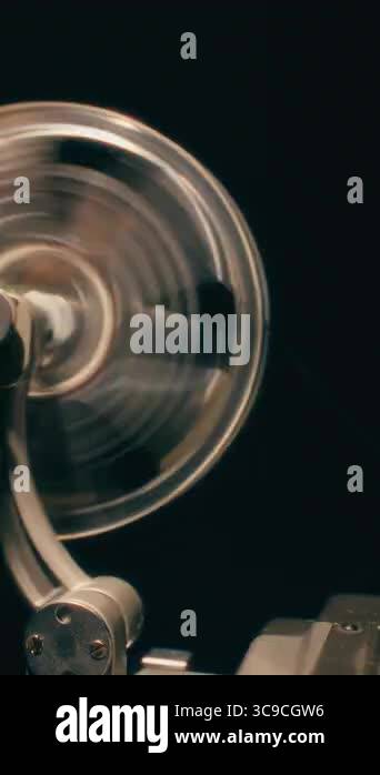 A detailed close-up shot showing a hand manually spinning a film reel ...