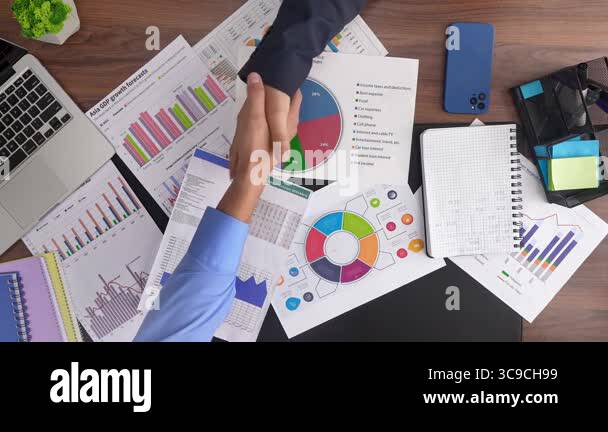 Image showing a business handshake over various financial documents ...