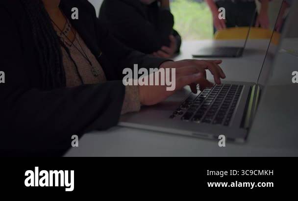 Hands typing on laptop keyboard during office meeting as camera slowly ...