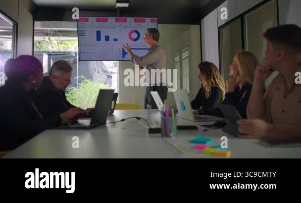 Male manager presenting data to diverse business team in modern ...