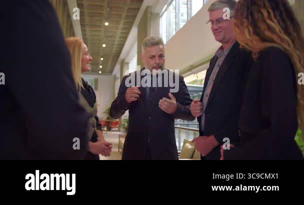 Corporate manager addressing diverse team in office hallway, leading ...
