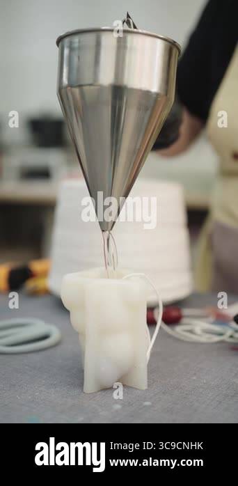 Professional candle maker carefully pouring vibrant red wax through ...