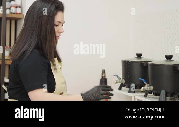 Woman professional candle maker carefully melting wax, preparing ...