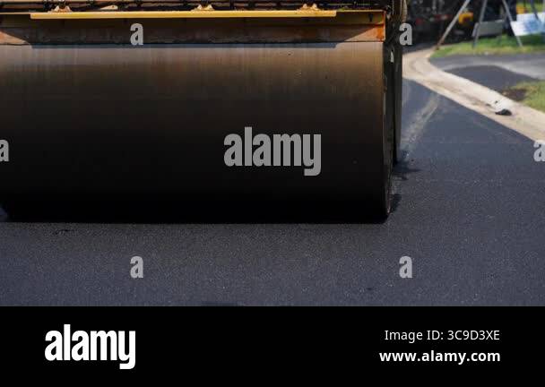 Road roller , steamroller in action, pressing down freshly laid asphalt ...