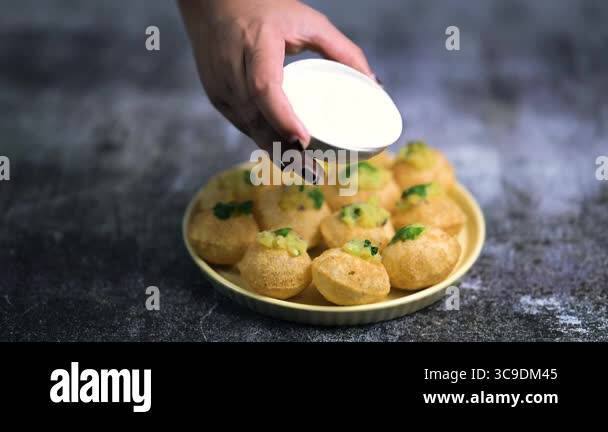 Close up of Indian street food fuchka on a glass with sour spicy water ...