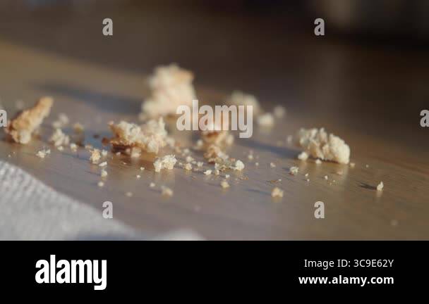 Small crumbs are spread across a wooden table after enjoying a snack ...