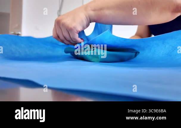 A close-up view of a hand wrapping a surgical tool with blue and green ...