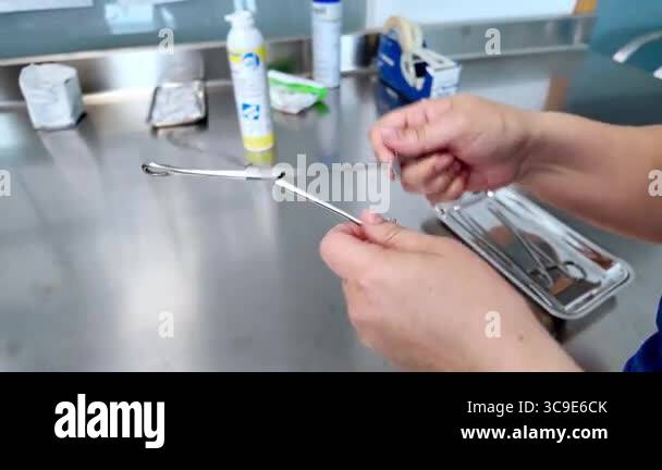 A hand holds a sterile stainless steel medical instrument, emphasizing ...