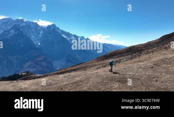 Backpacking woman climbing up on steep cliff edge at high altitude ...