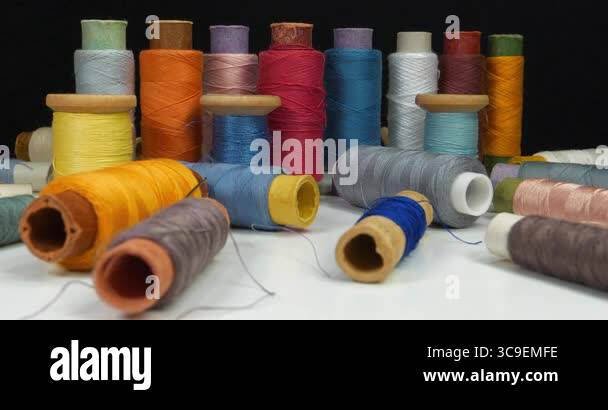 Spools with varicolored threads on black background. Cinema 4K 60fps ...