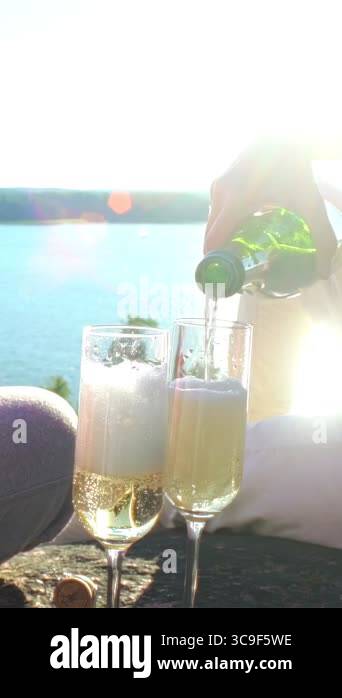 Two happy female friends sharing a bottle of champagne on the top of ...