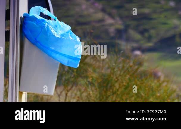 Trash can with blue plastic bag inside hanging on camper rv door ...