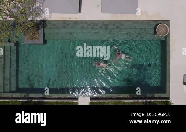 boy and girl spinning and swimming together in a luxurious pool Stock ...
