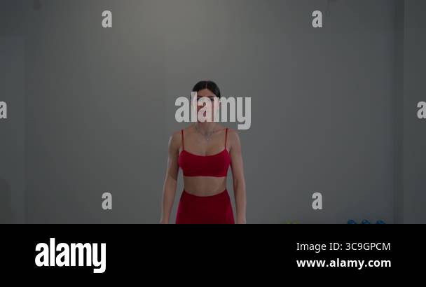 girl in a red outfit engages in jumping jacks in a well lit indoor ...