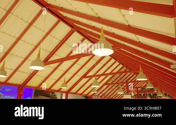 A modern interior view of a building featuring a sloped roof with red ...
