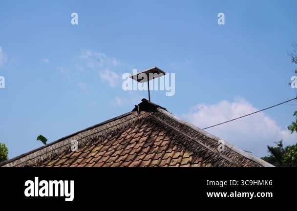 A solar panel mounted on the roof of a traditional house under a clear ...