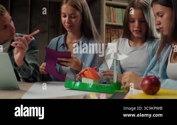 Caucasian school classmates pupils teens making paper house task ...