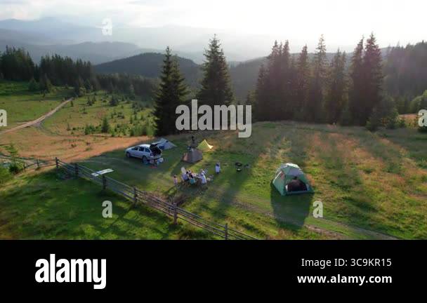 Aerial view of picturesque campsite on grassy hill, surrounded by ...