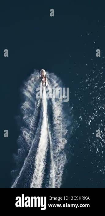 Aerial view of a jet ski speeding across dark blue water, leaving a ...