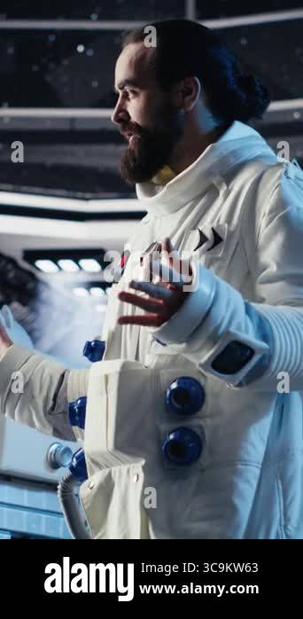 Vertical video Joyous astronaut greeting command center researchers during videocall, presenting ...