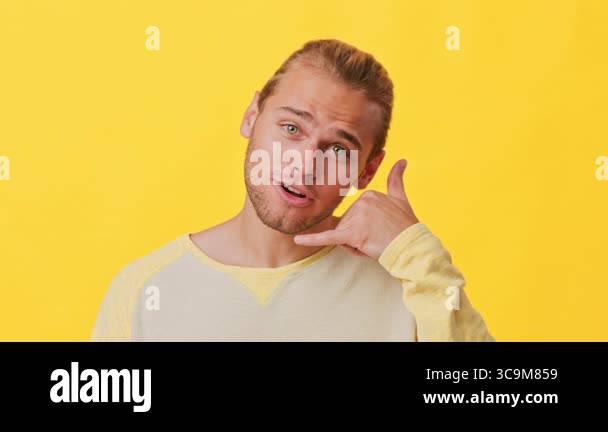 A stylish young man with mixed ethnicity gestures a phone call sign ...