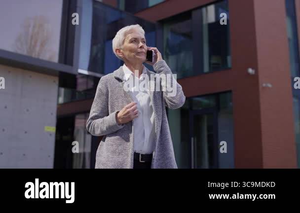 Smiling older businesswoman having a phone conversation outside a ...