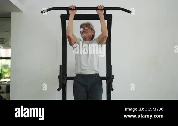 Asian senior man maintaining strength and fitness by performing pull ...