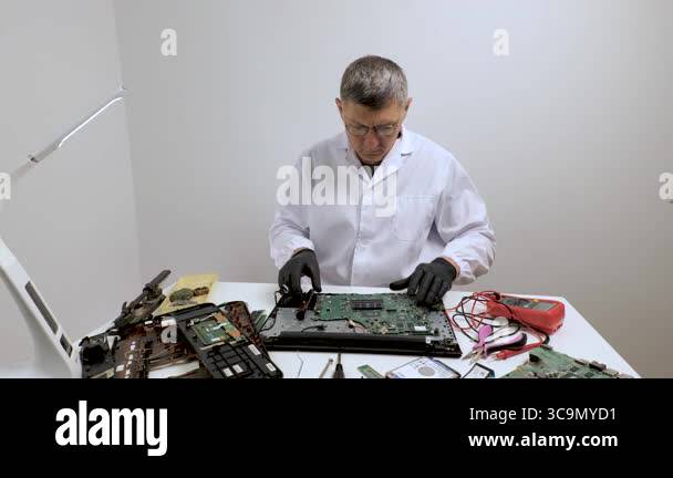Technician cleaning motherboard, Man in white lab coat and black gloves ...