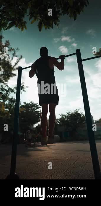 Male bodybuilder doing pull-ups on bar during sunset workout, Athlete ...
