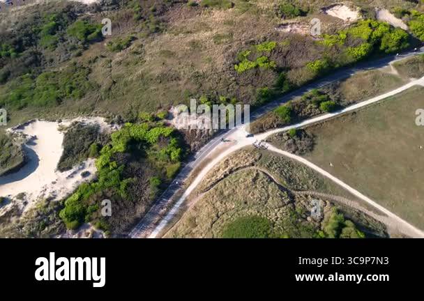 An aerial view of winding trails through green hills and sand dunes ...