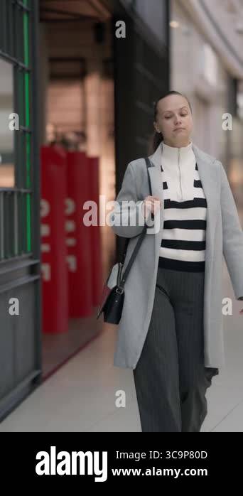 An elegant woman walks through a shopping center, looking at the ...