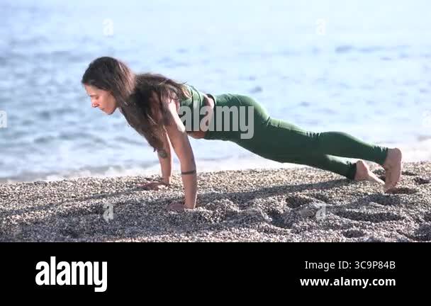 Yoga instructor practicing dolphin pose variations on a peaceful beach ...