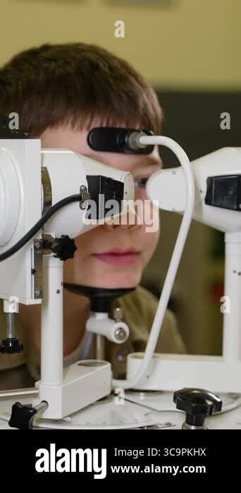Ophthalmology clinic doctor examining eyesight of child patient using special equipment ...